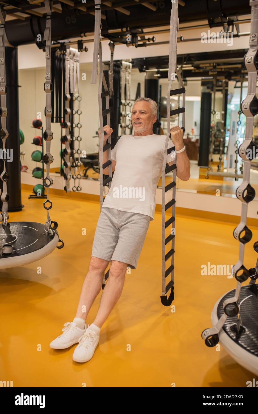 A man hanging on gym machine and looking positive Stock Photo - Alamy