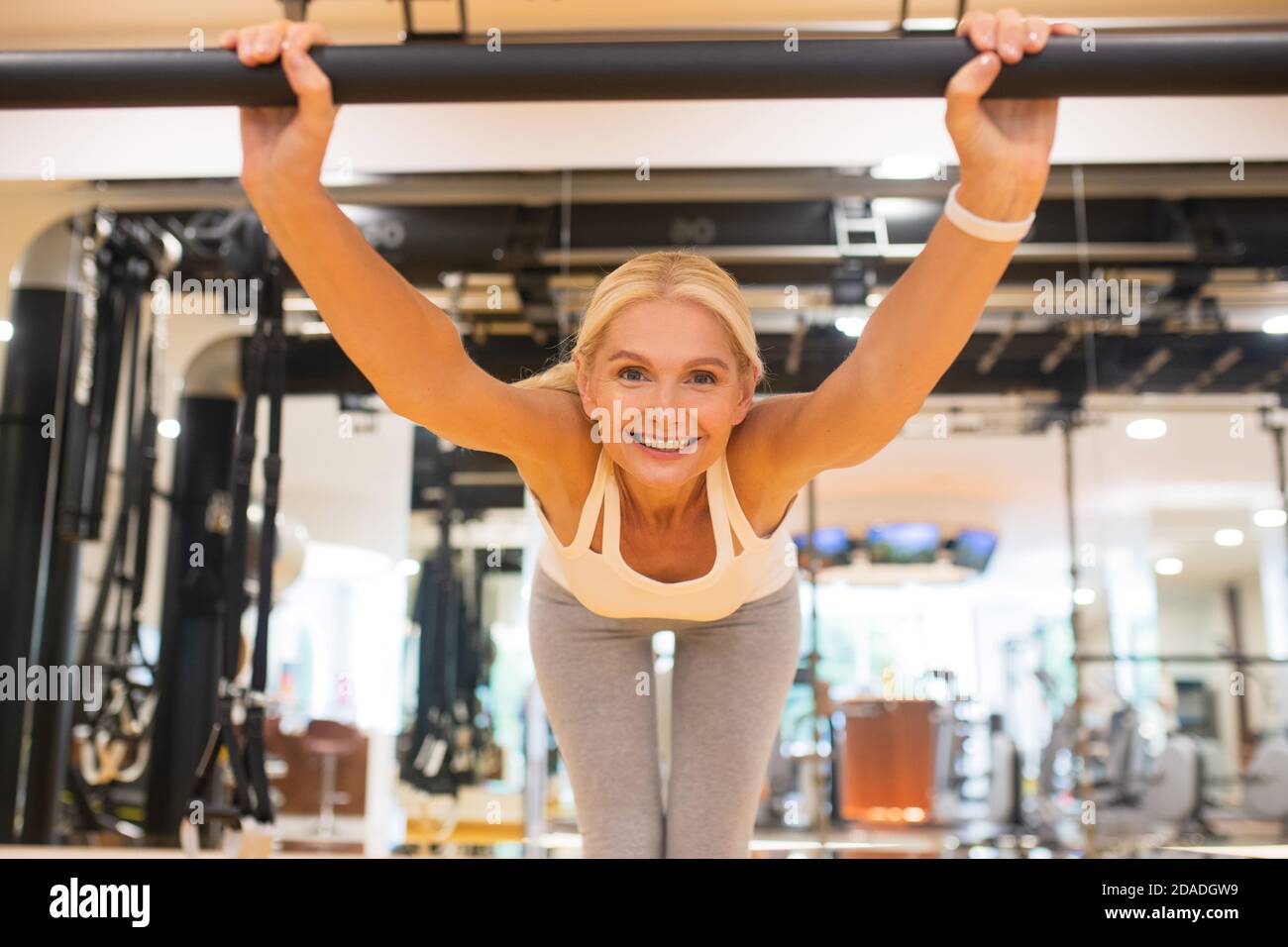 A woman leaning forward doing exercises in gym and smiling Stock Photo ...