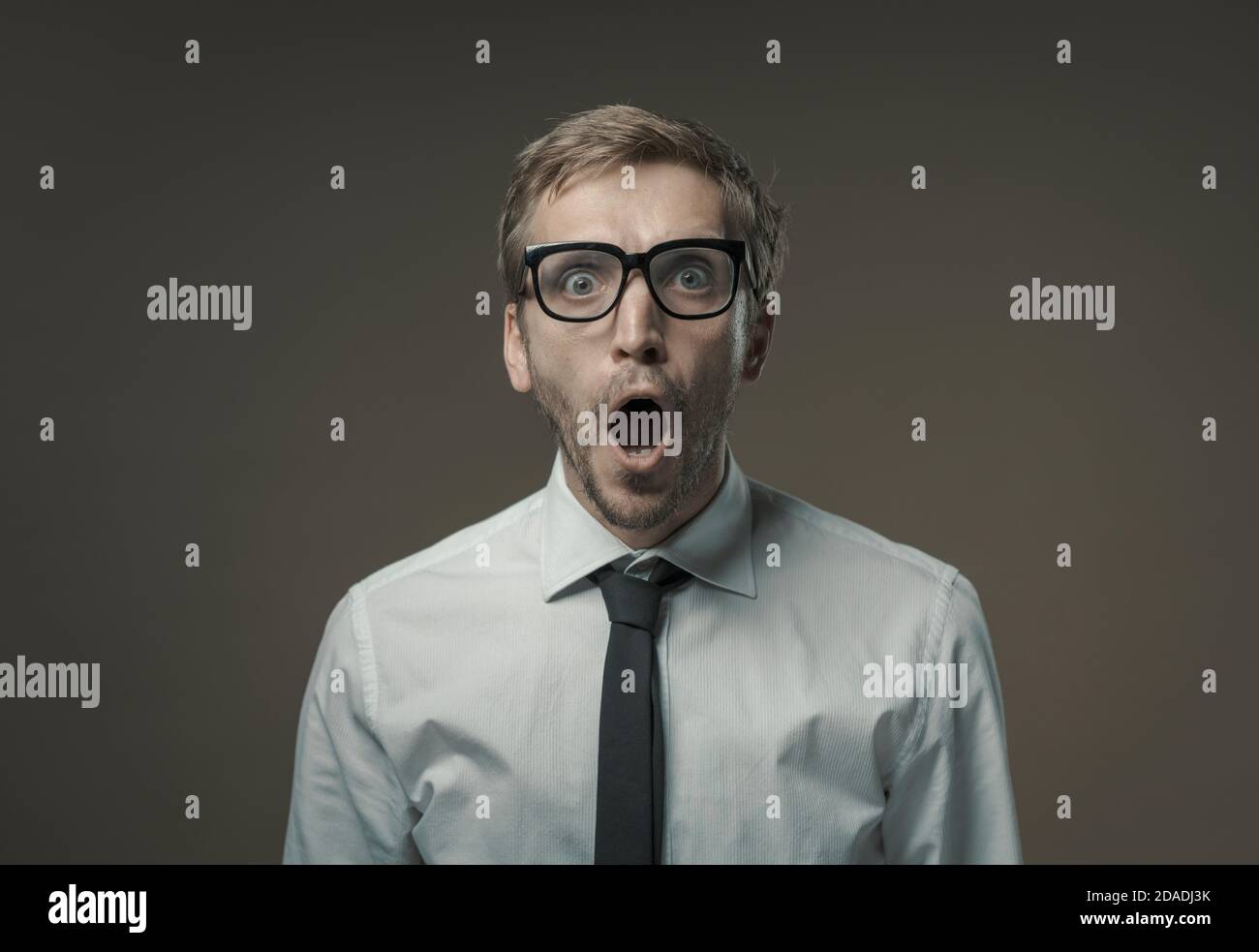 Young businessman with glasses staring at camera and gasping, he is ...