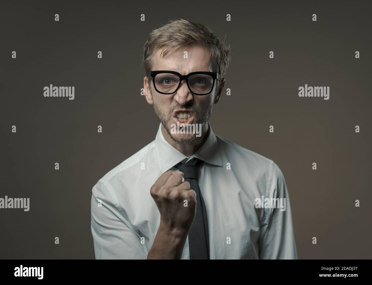 Angry aggressive businessman looking at camera and showing his fist ...