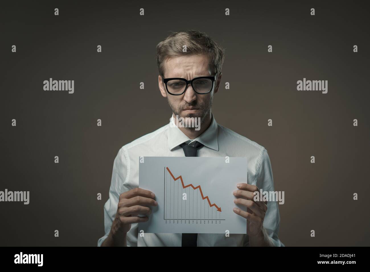Sad businessman holding a negative financial chart, bankruptcy and ...