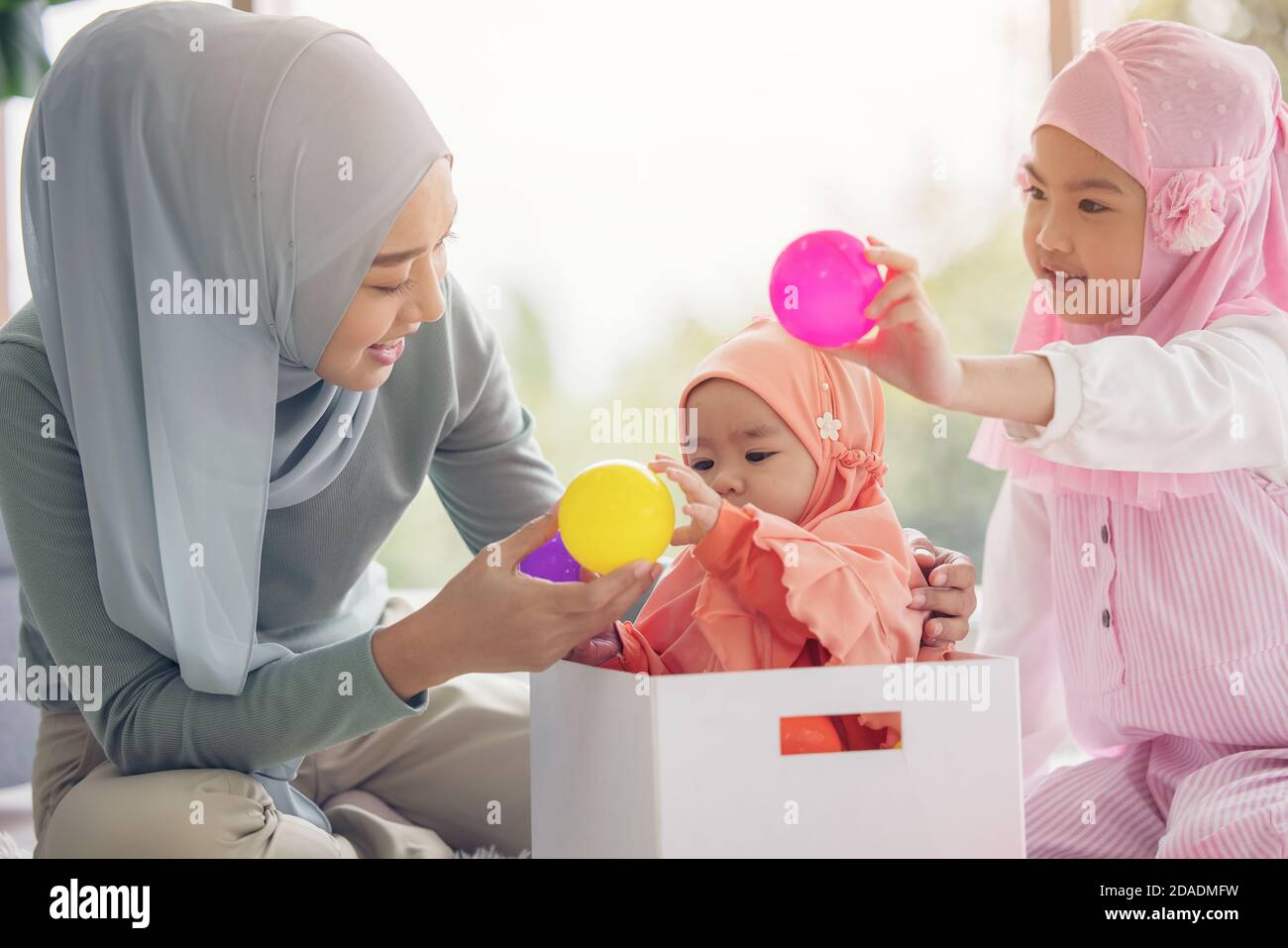 Muslim mom in hijab is her little daughter sitting in the living room ...