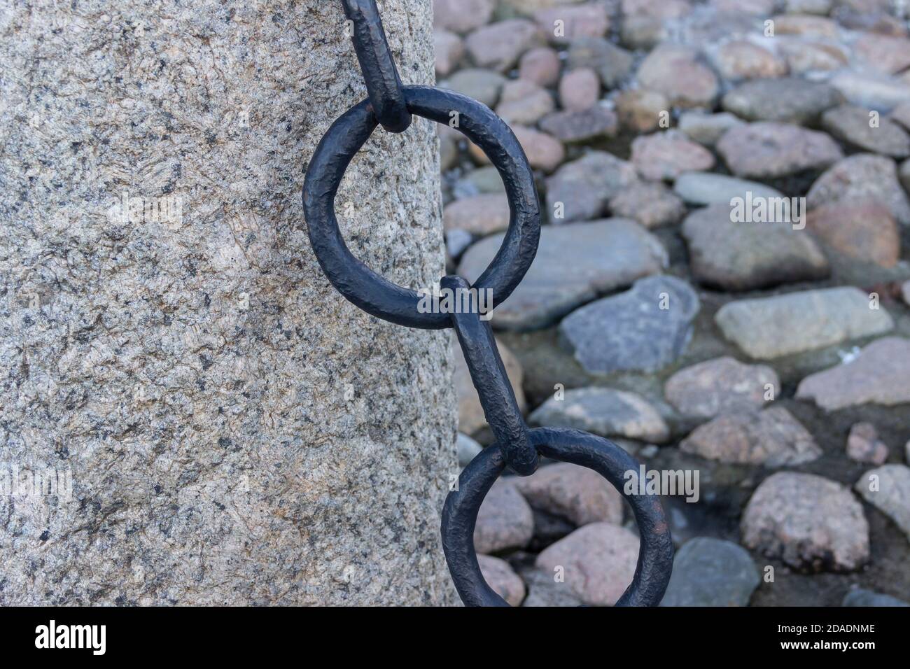 Old forged rusty chain with peeling paint on the background of paving ...