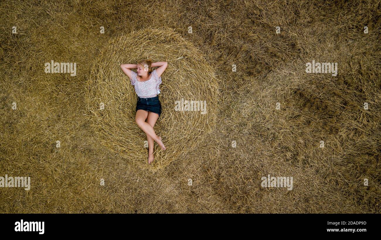 Young girl posing on a round haystack, top view Stock Photo - Alamy