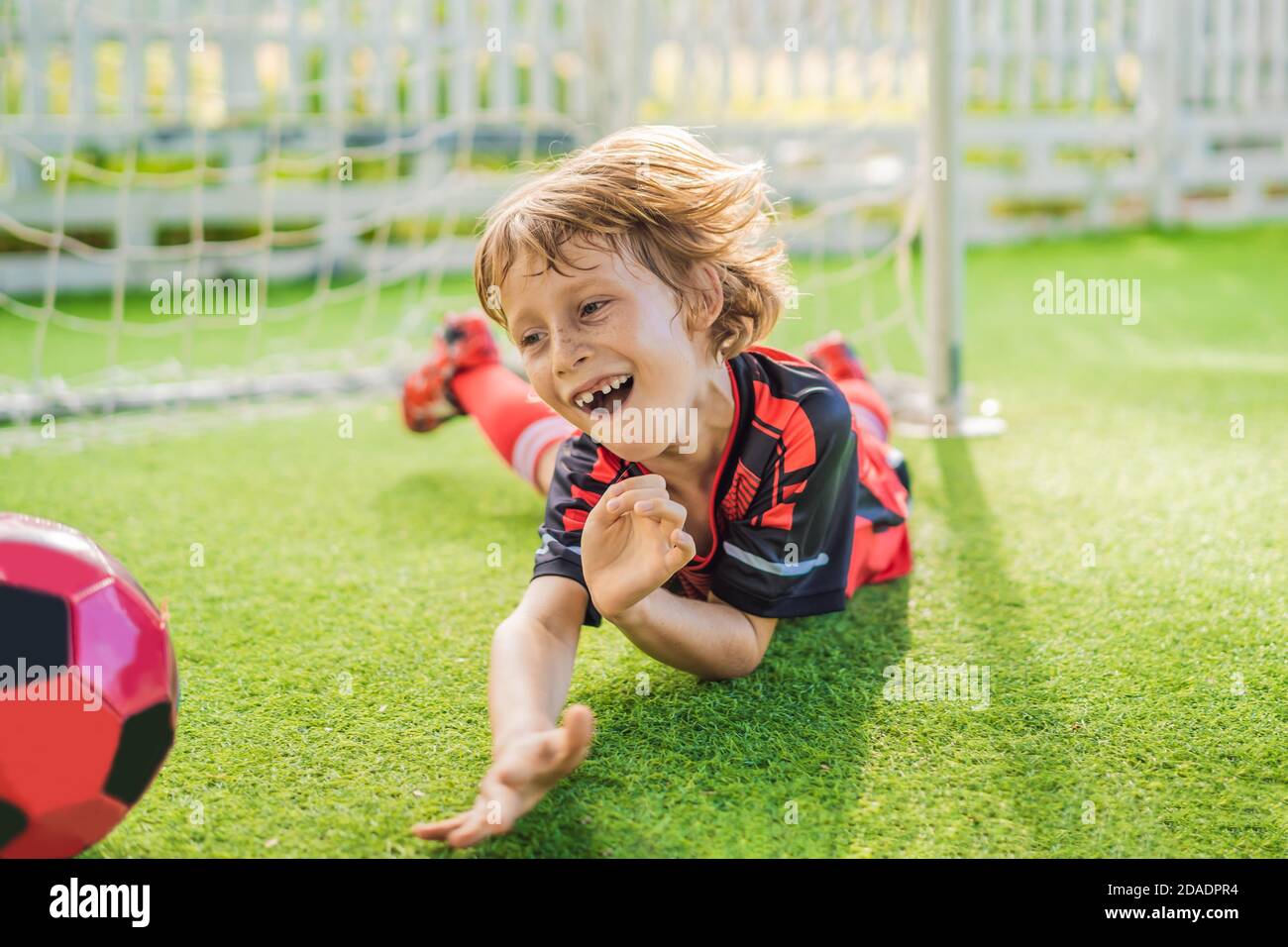 Little cute kid boy in red football uniform playing soccer, football on ...