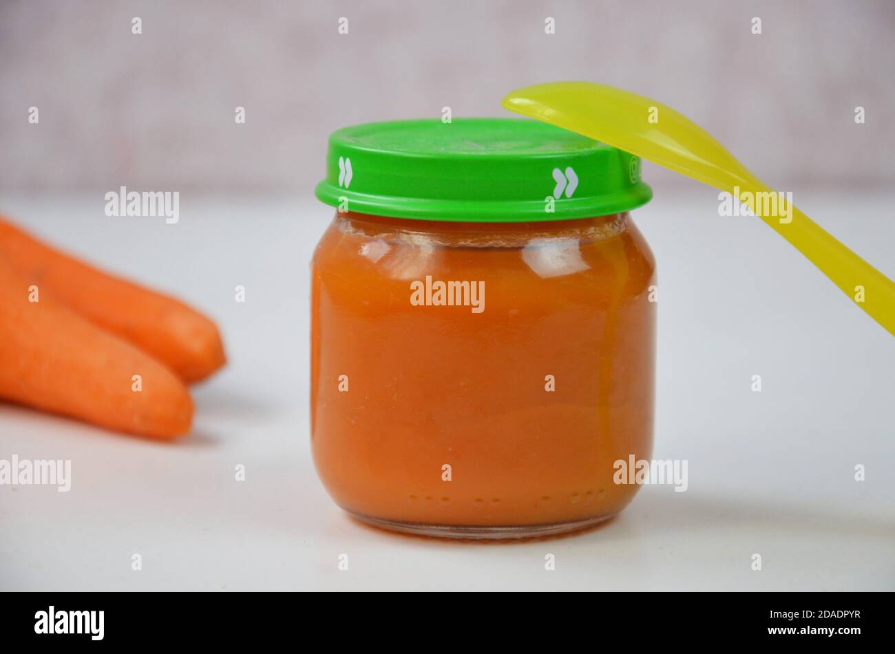 baby mashed with spoon in glass jar on white background Stock Photo - Alamy