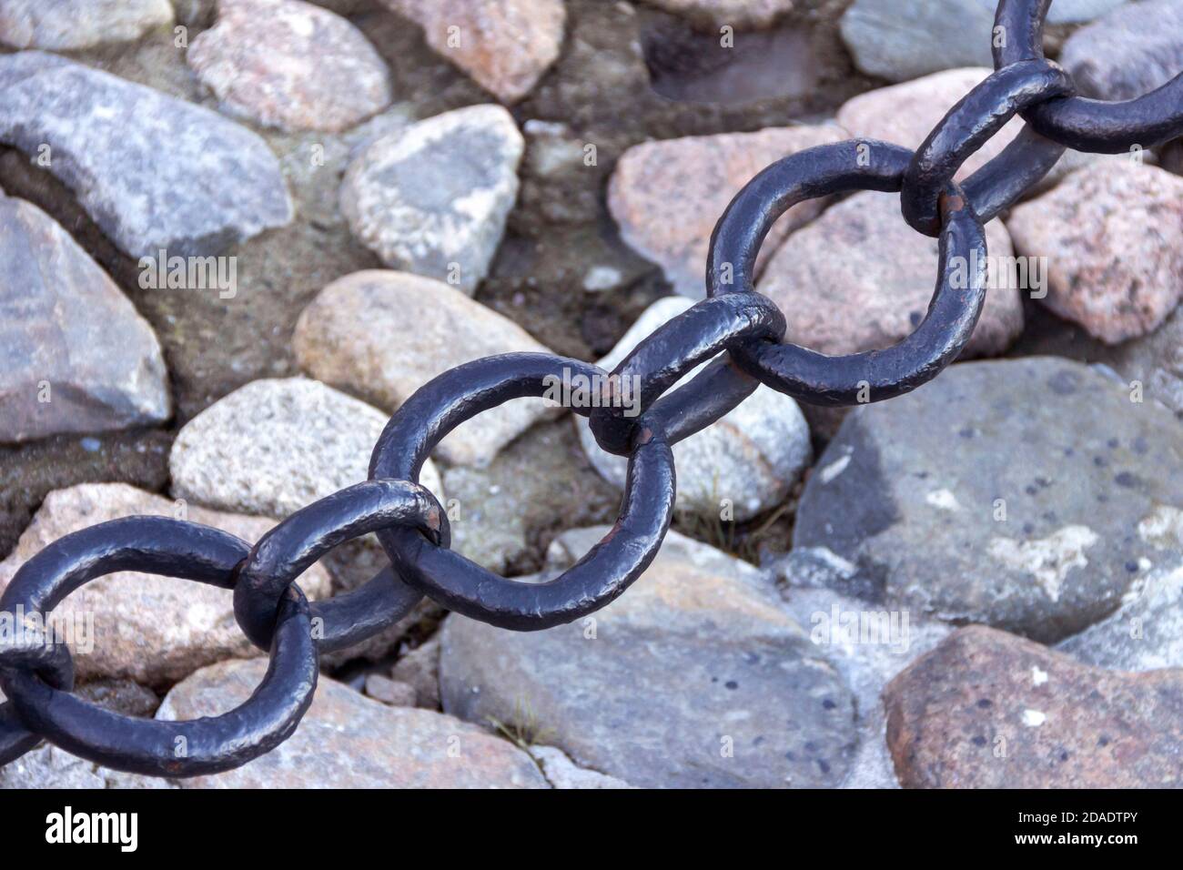 Old forged rusty chain with peeling paint on the background of paving ...