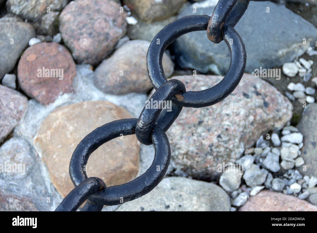 Old forged rusty chain with peeling paint on the background of paving ...
