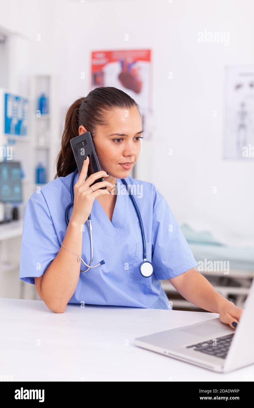 Medical receptionist talking with patient in hospital office and using ...
