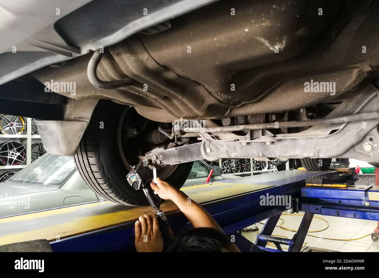 Mechanic adjusting car axle camber in workshop during wheel alignment ...