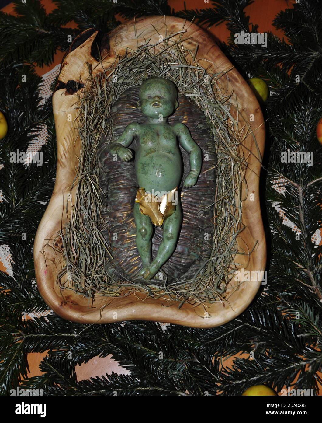 a green baby jesus in a small christmas crib with hay Stock Photo - Alamy