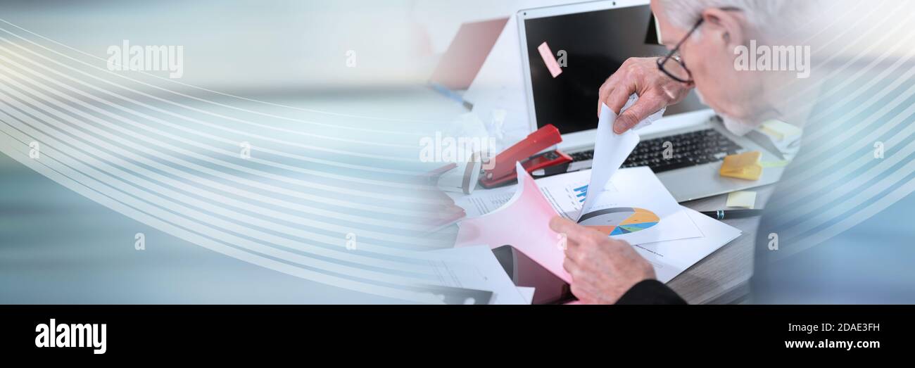 Disorganized businessman looking for documents on his messy desk ...