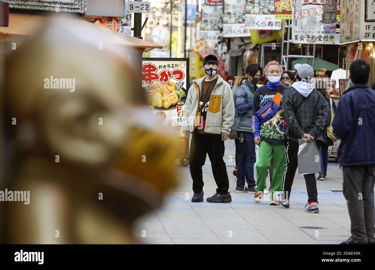 People wearing face masks walk in Osaka's Shinsekai area in western ...