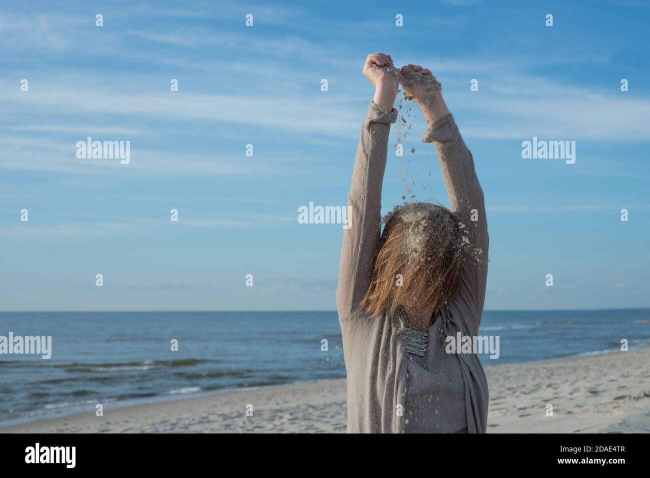Woman pouring sand on her head on the beach Stock Photo - Alamy