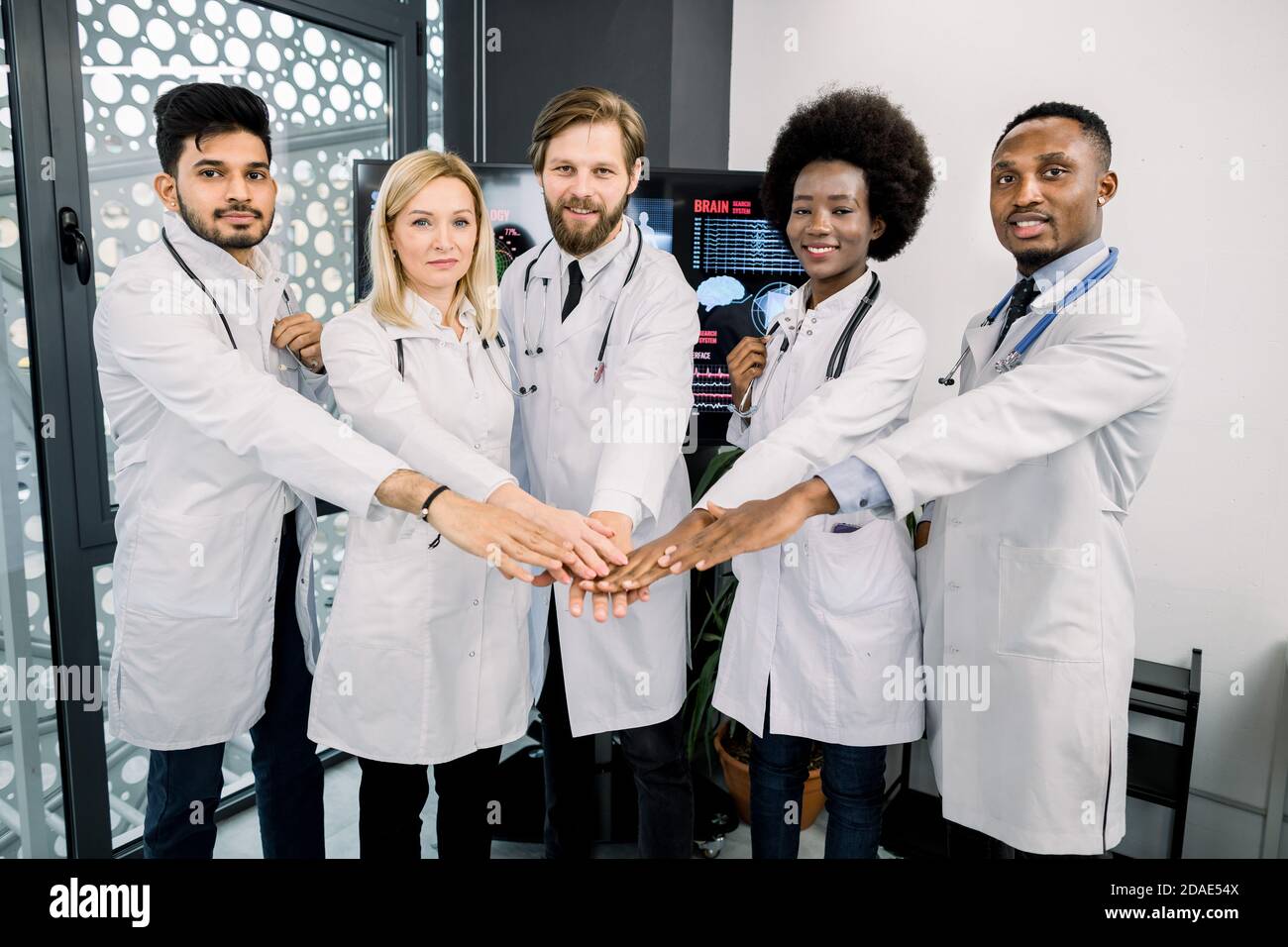 Smiling international medical team of five female and male doctors ...