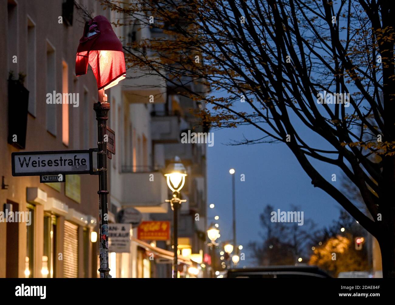 Berlin, Germany. 11th Nov, 2020. A street lamp is hung with a red T ...