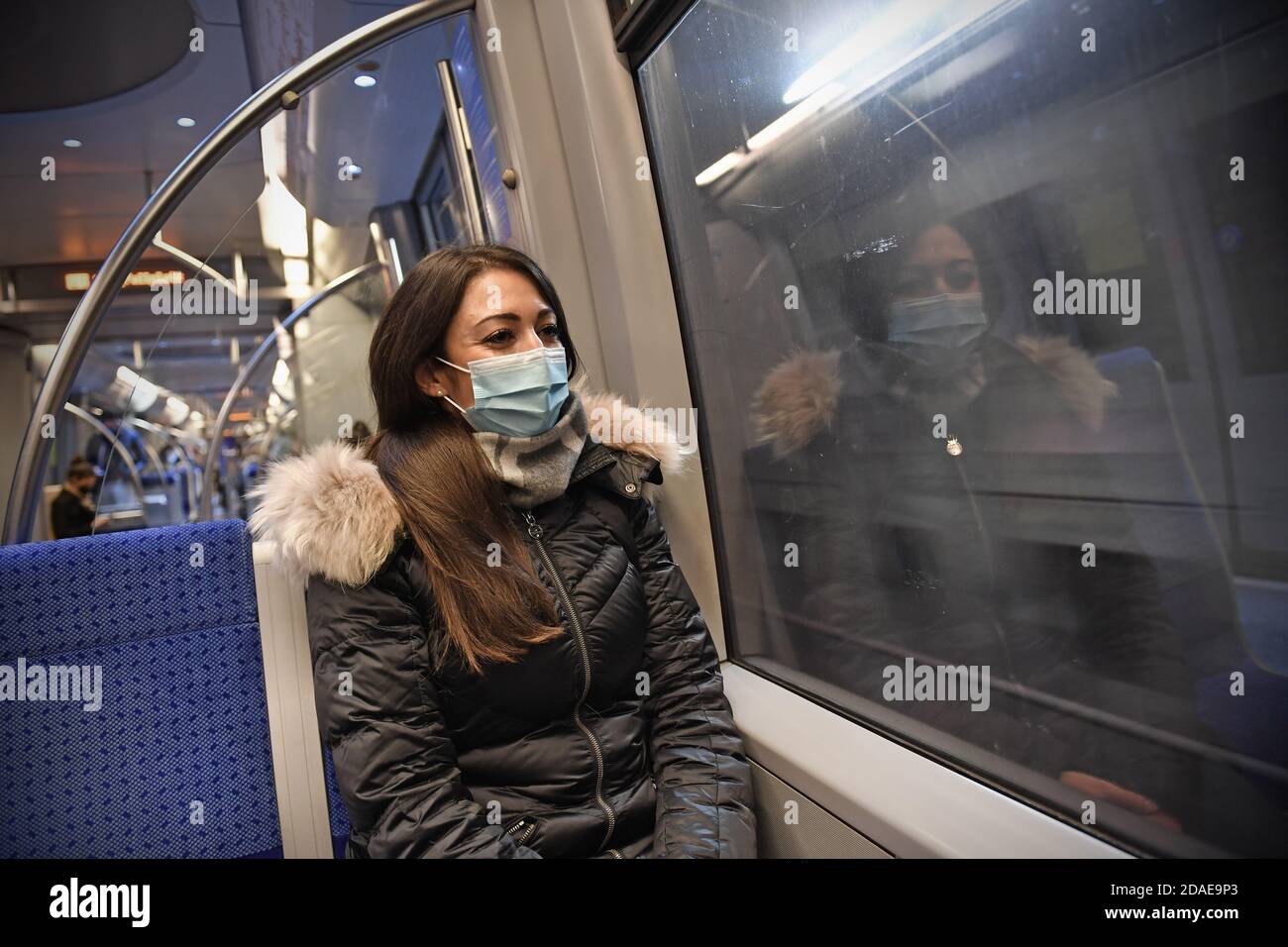 Mask compulsory in public transport. Young woman sitting in a train of ...