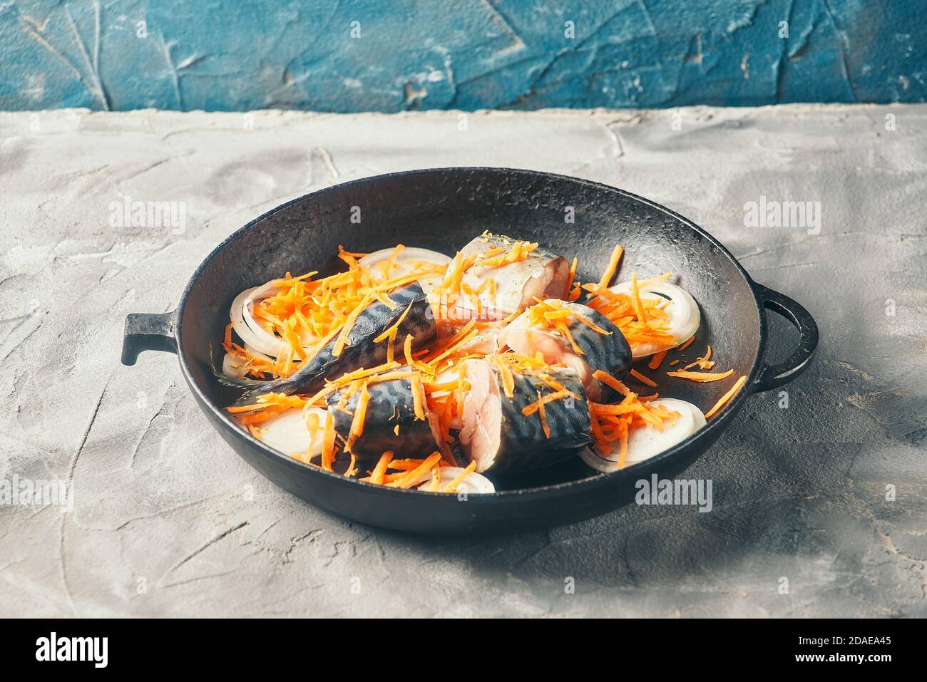 grated carrots and sliced fresh mackerel fish lie in a frying pan for ...