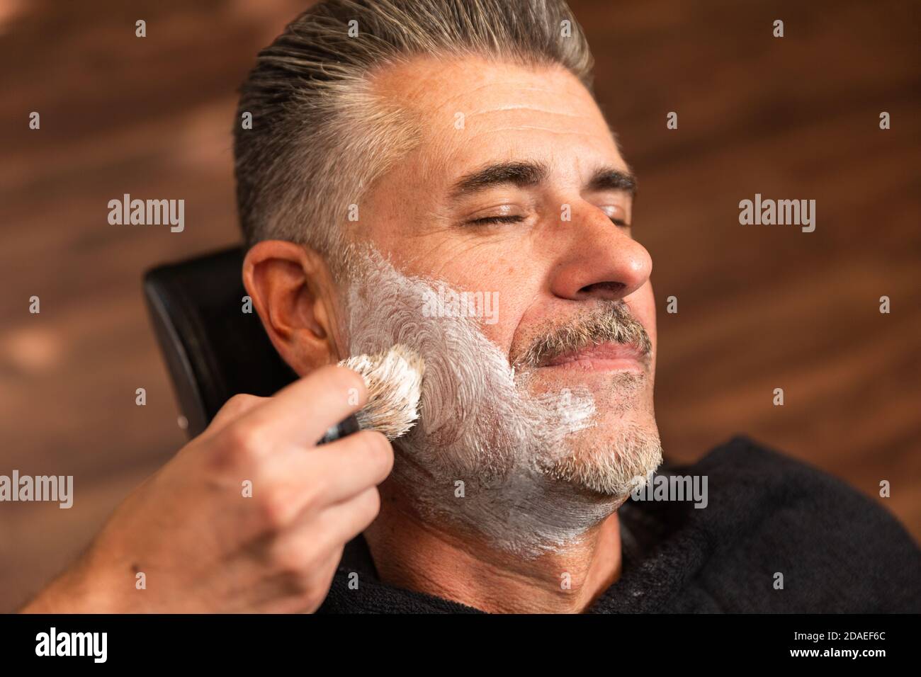 barbershop, barber's hand puts shaving foam with a razor blade on a ...