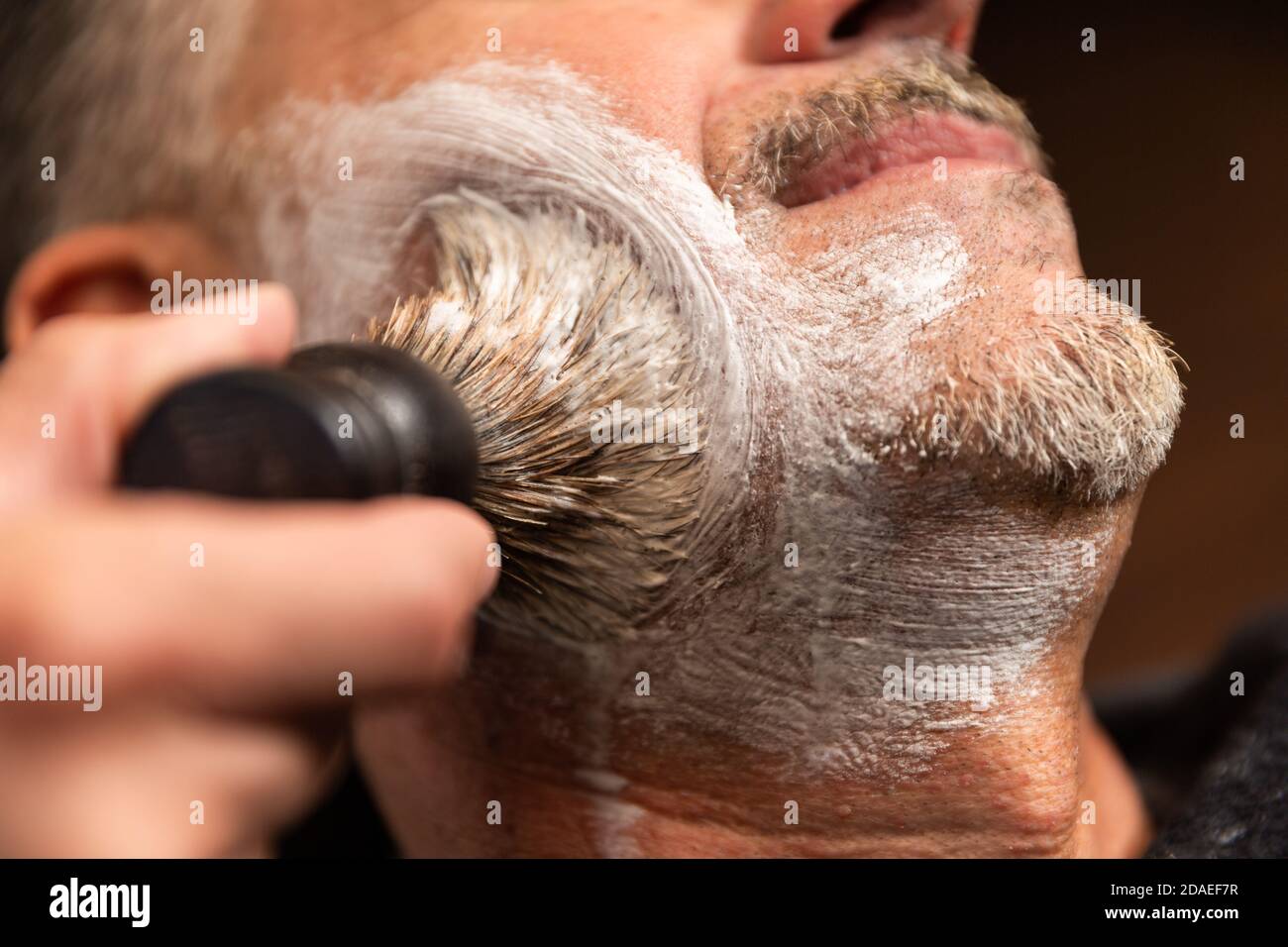 barbershop, barber's hand puts shaving foam with a razor blade on a ...
