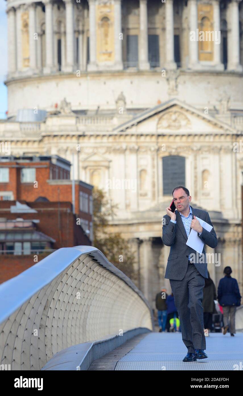 London, England, UK. Man walking over the Millennium Bridge, talking on ...