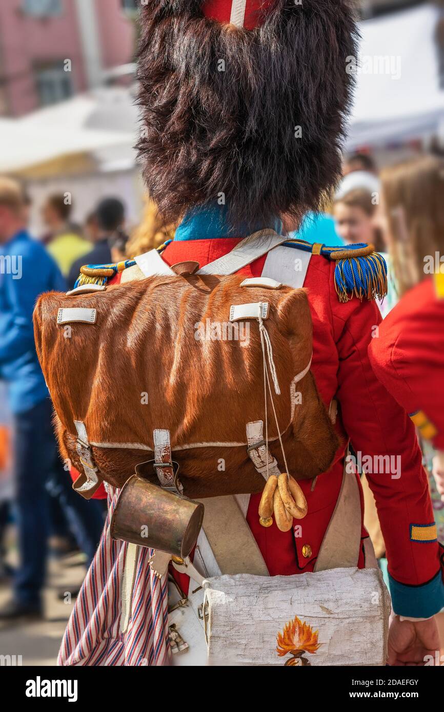 Young man back to us in folk dress and fluffy hat with backpack ...