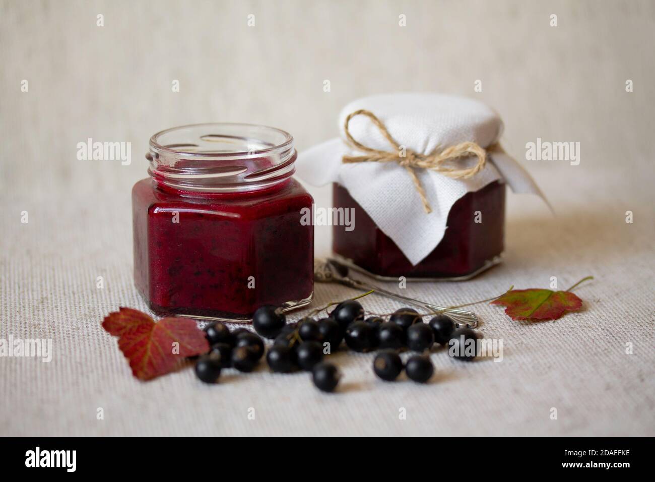 Black currant jam in glass jars. Fresh berries with leaves and stems ...