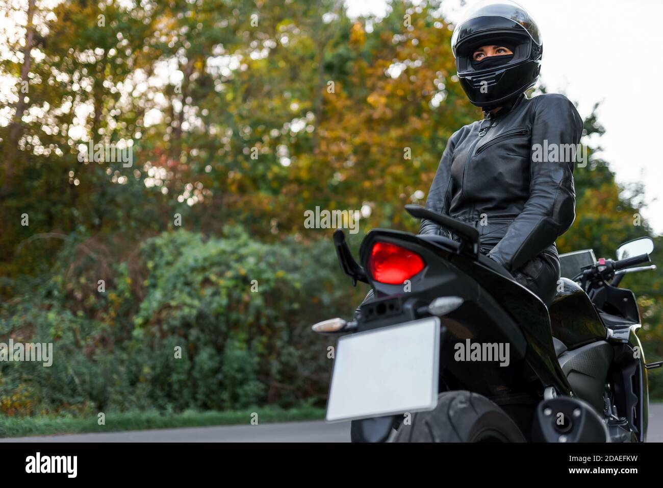 Biker woman in black uniform sits on a motorcycle Stock Photo - Alamy
