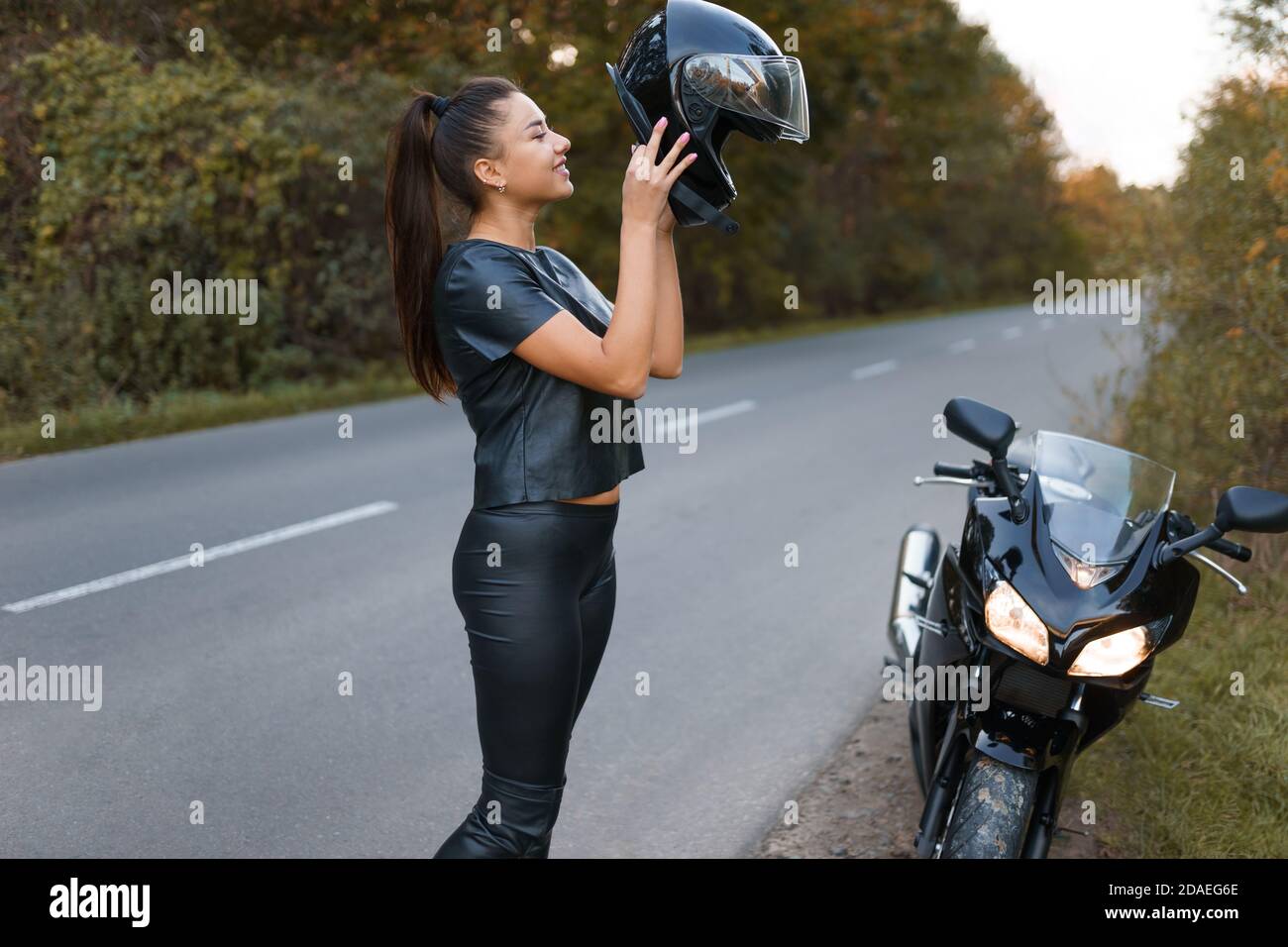 Young female motorcyclist puts a helmet on her head Stock Photo - Alamy
