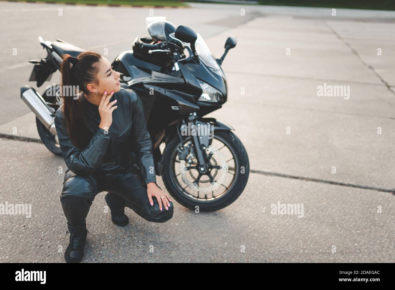 Biker girl in a leather suit near her motorcycle Stock Photo - Alamy