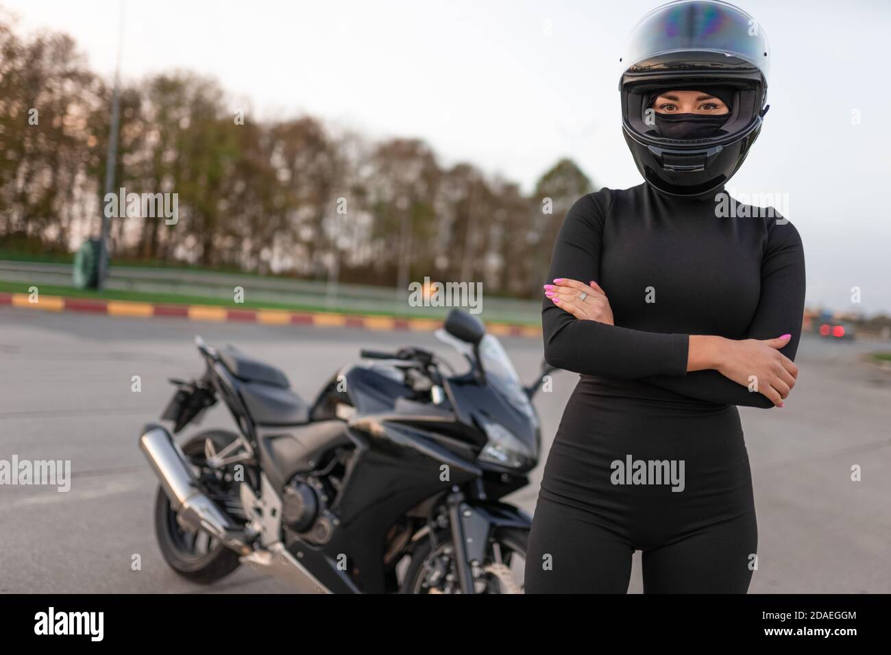 Female motorcyclist in helmet and black clothes near the motorcycle ...