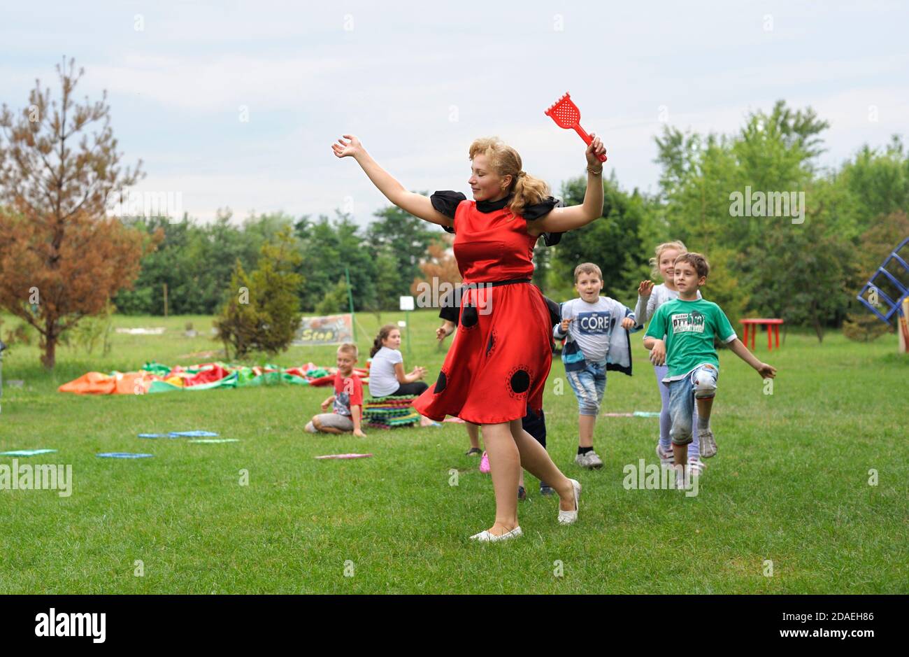 Young attractive nanny dancing with children at the playground. June 12 ...