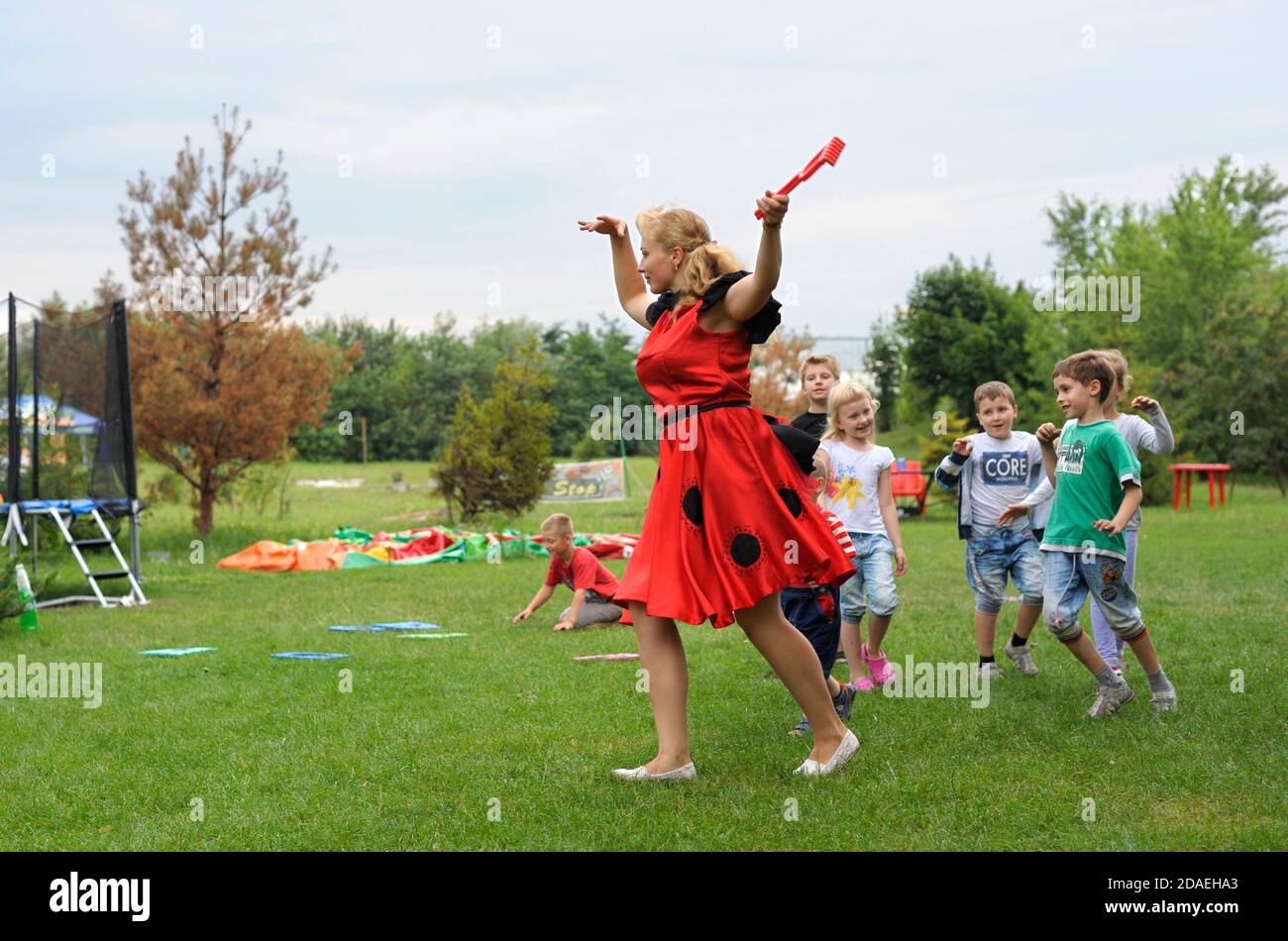 Young attractive nanny dancing with children at the playground. June 12 ...
