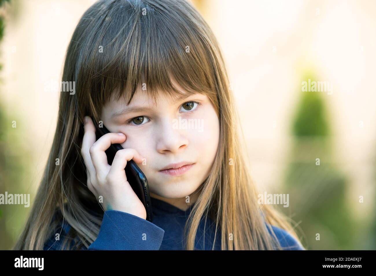 Portrait of pretty child girl with long hair talking on cell phone ...