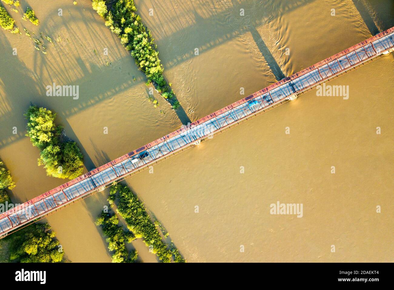 Aerial view of a narrow road bridge stretching over muddy wide river in ...