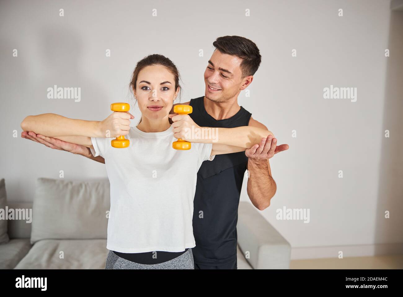 Friendly coach adjusting arm position of a sporty lady Stock Photo - Alamy