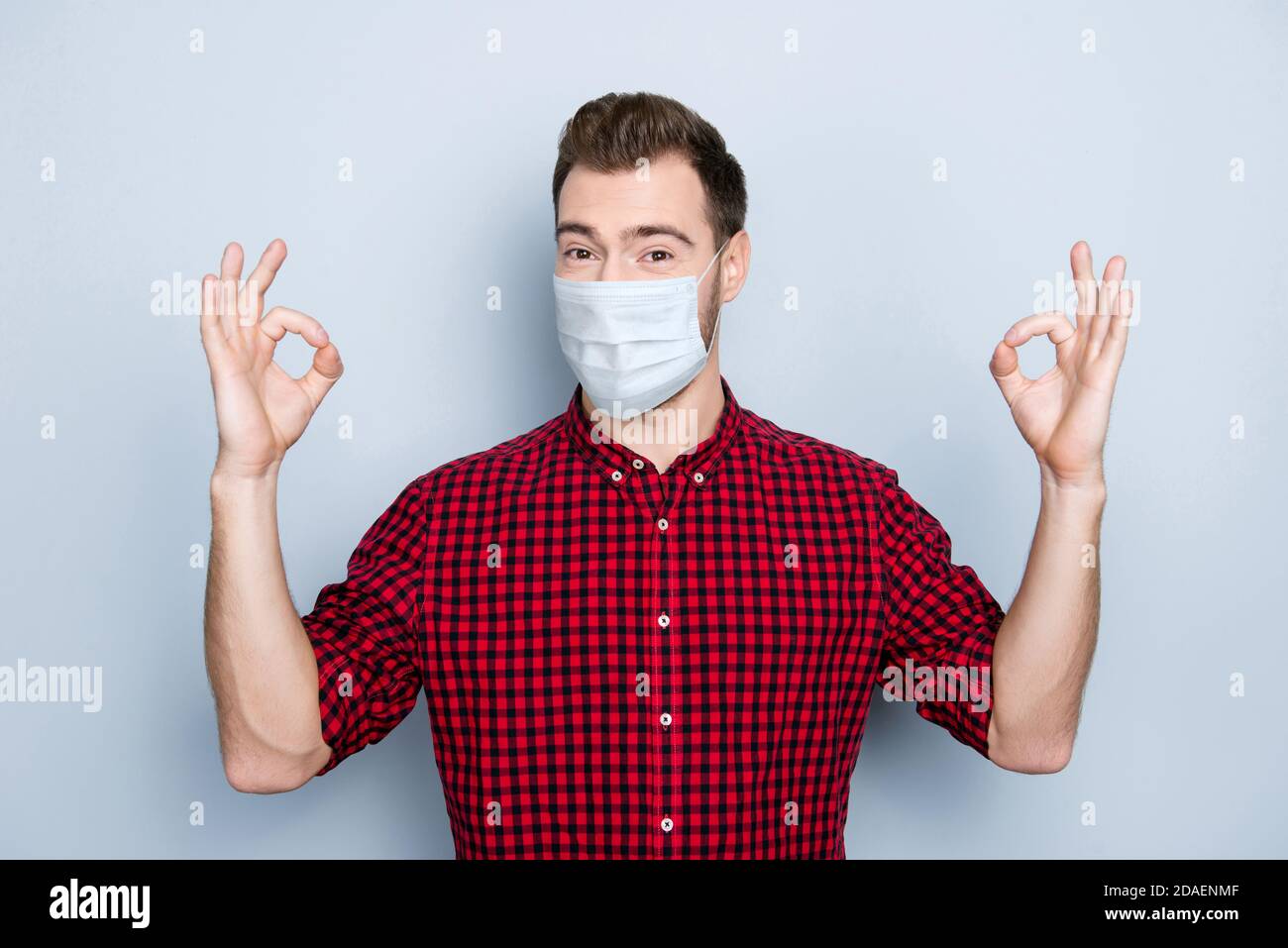 Portrait of man showing two ok-signs wearing white face mask isolated ...