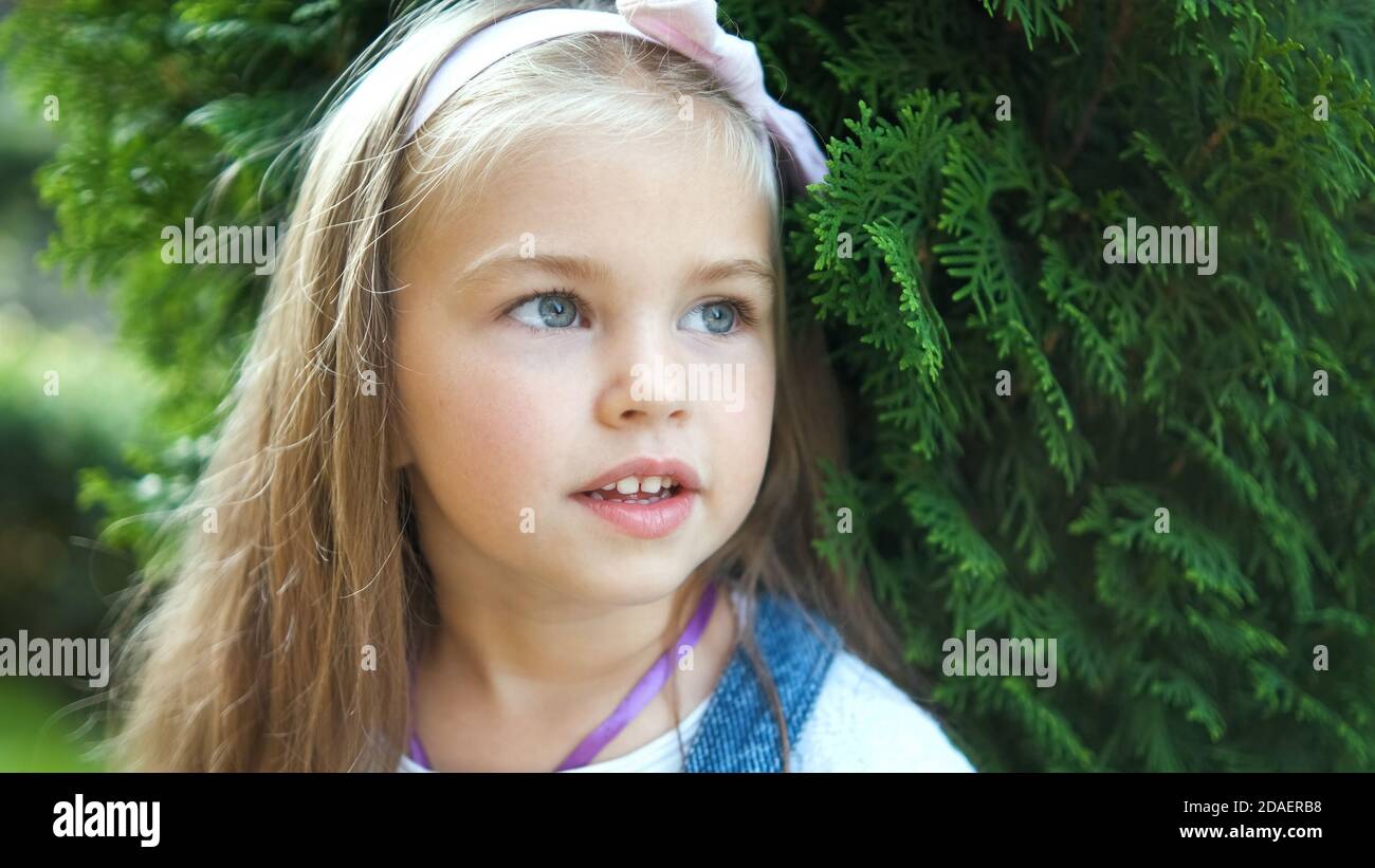 Portrait of pretty little child girl standing outdoors in summer park ...