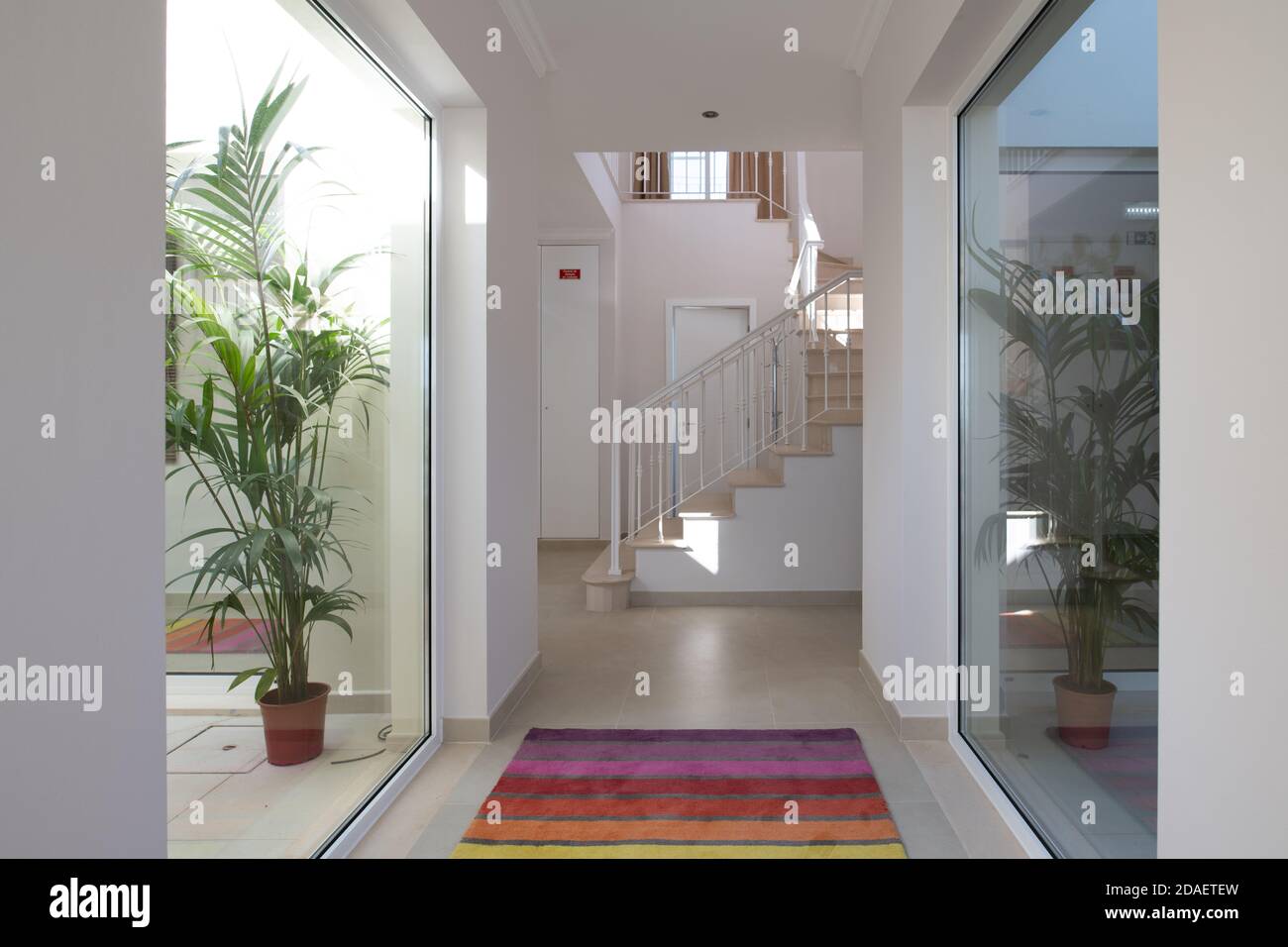 Corridor in modern home with stairs at the end and glass windows to ...