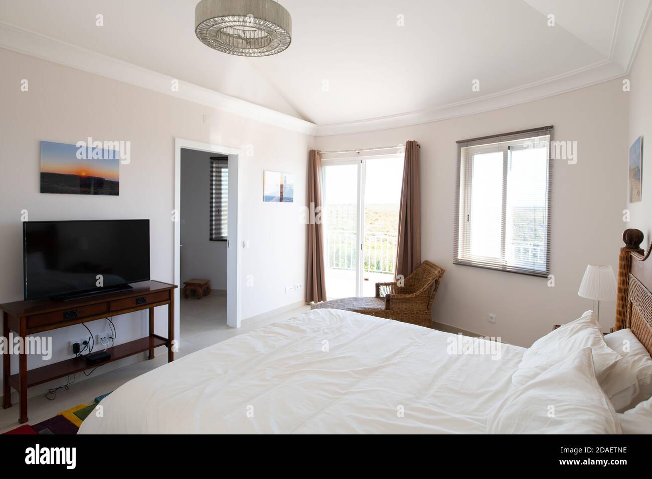 Master bedroom with wooden furniture, white bedding and sliding doors ...