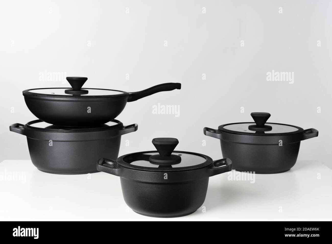 Black cooking pots on grey background front view Stock Photo - Alamy