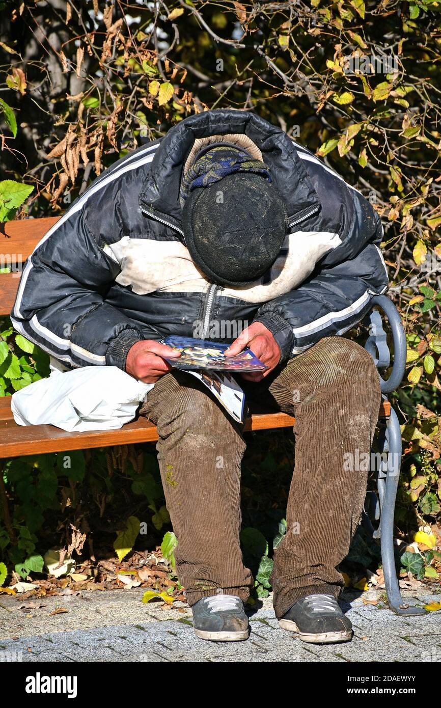 Homeless man sits on a park bench Stock Photo - Alamy