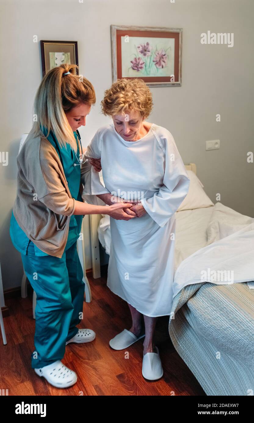 Caregiver helping elderly patient to stand up Stock Photo - Alamy
