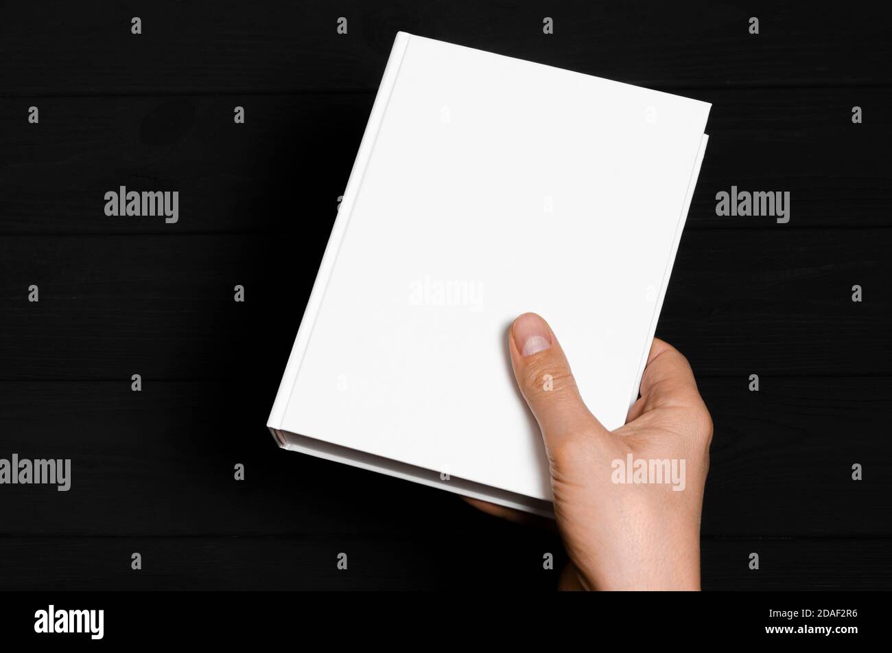 Men's hands holding closed book with blank cover on light background ...