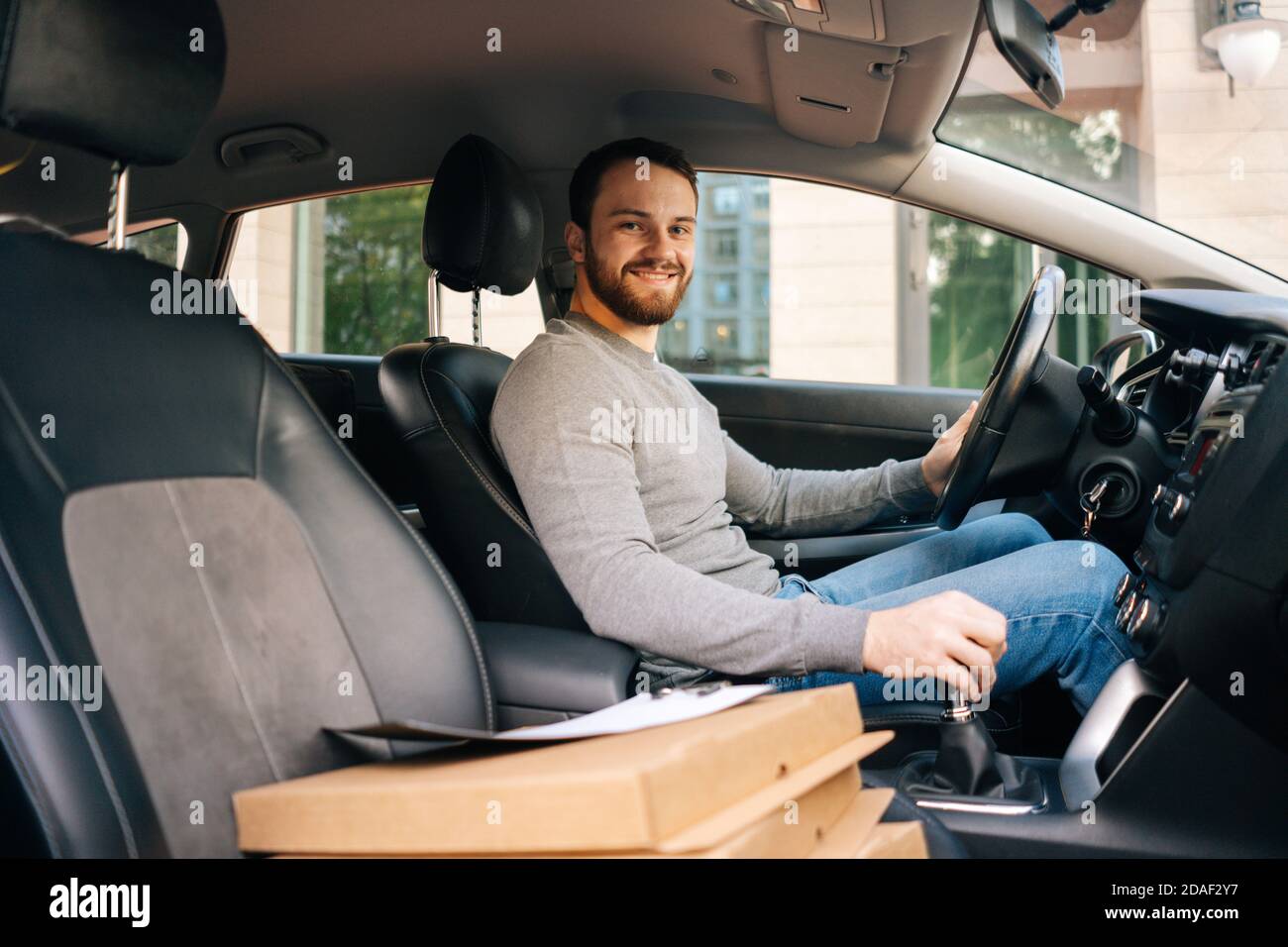 Professional bearded delivery man wearing casual clothes driving car ...
