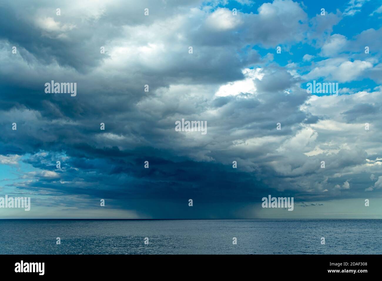 CLOUDBURST AT CENTER OF DISTANT CUMULONIMBUS RAIN CLOUD OVER EMPTY CALM ...
