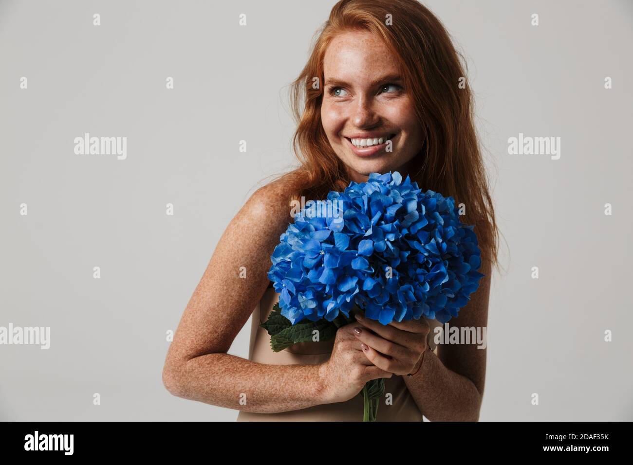 Image of optimistic redhead woman with freckles holding blue flowers ...