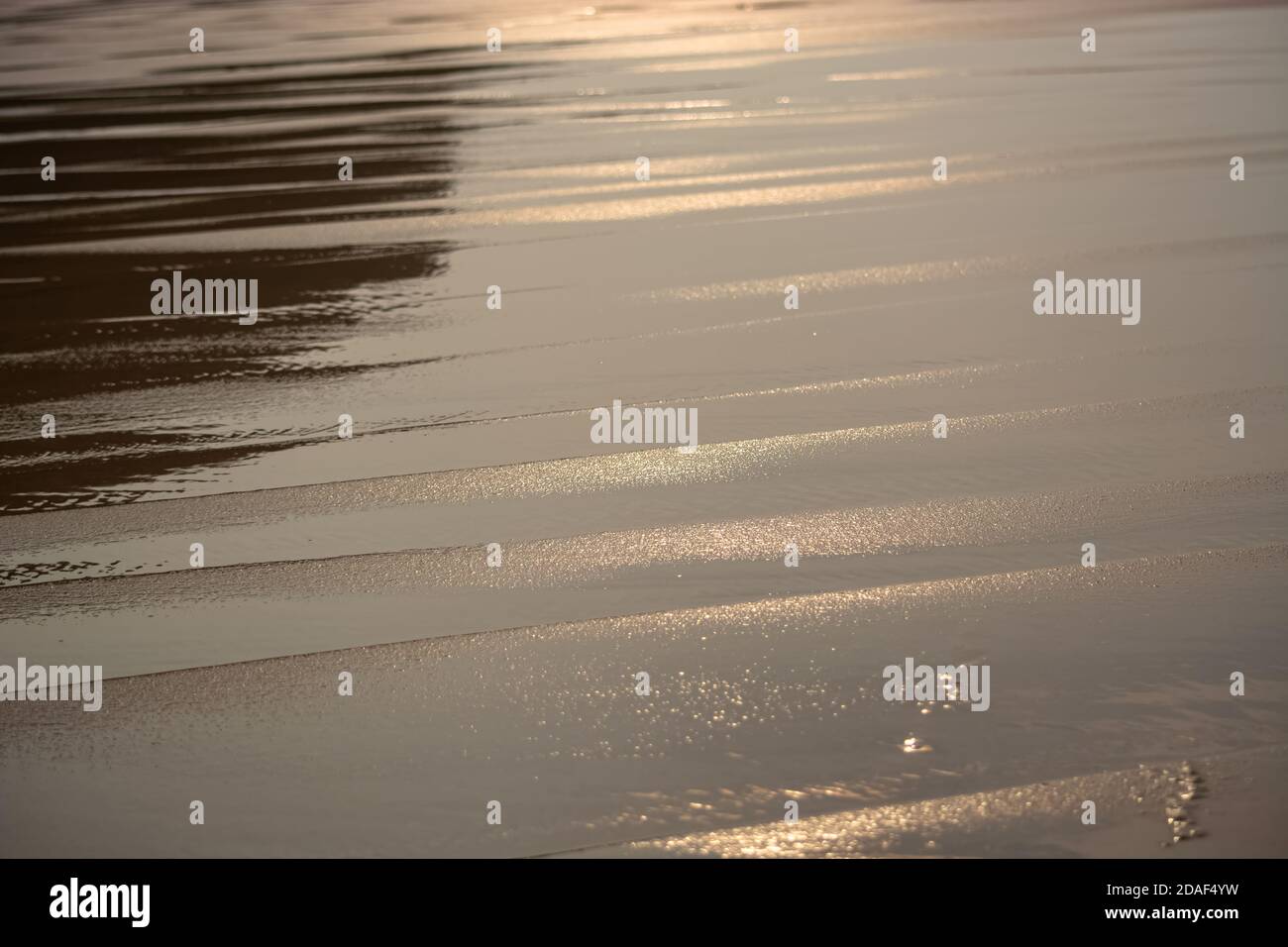 Seaside view with light effects and reflections in the water, wet sand ...