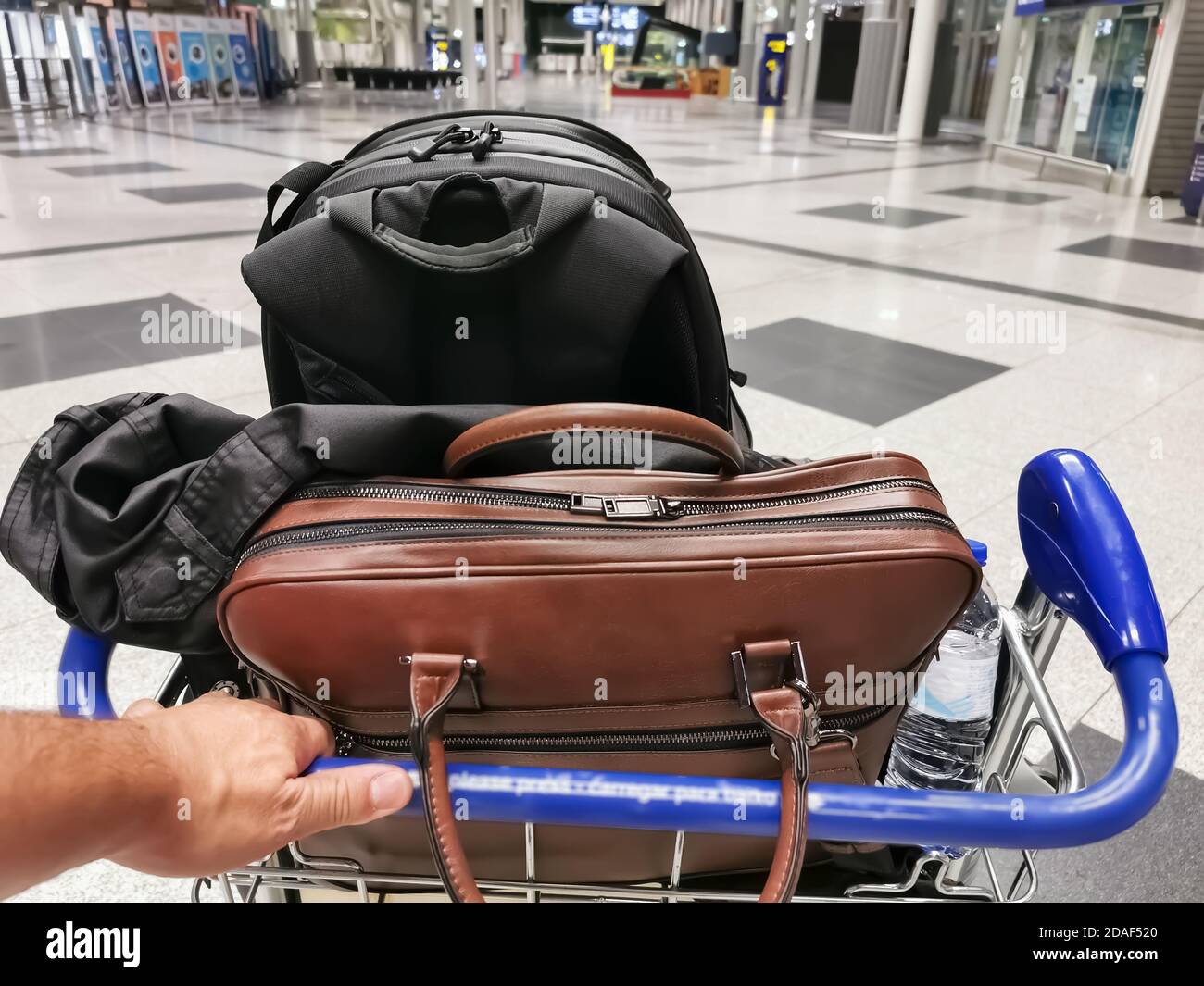 View of luggage trolley with suitcases and hand of traveler pushing ...