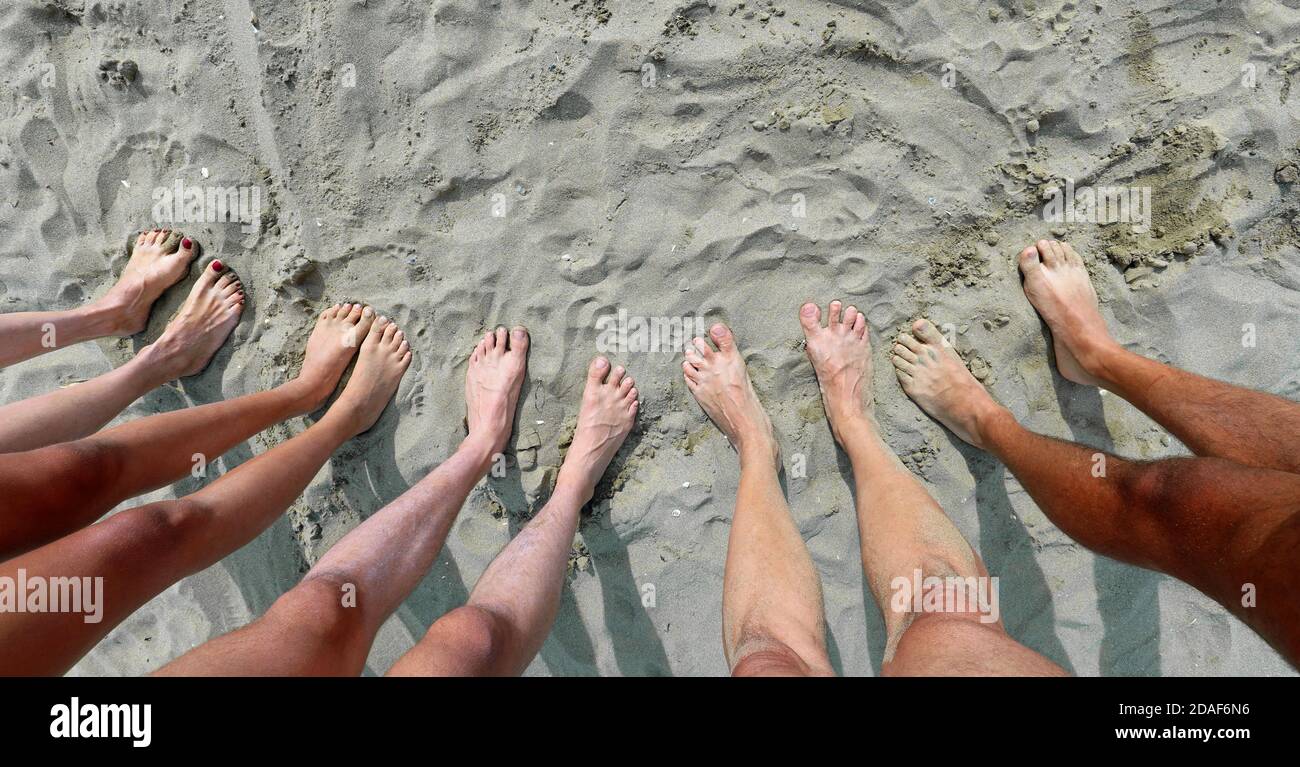 line of ten feet of a family of five on the sand by the sea in summer ...